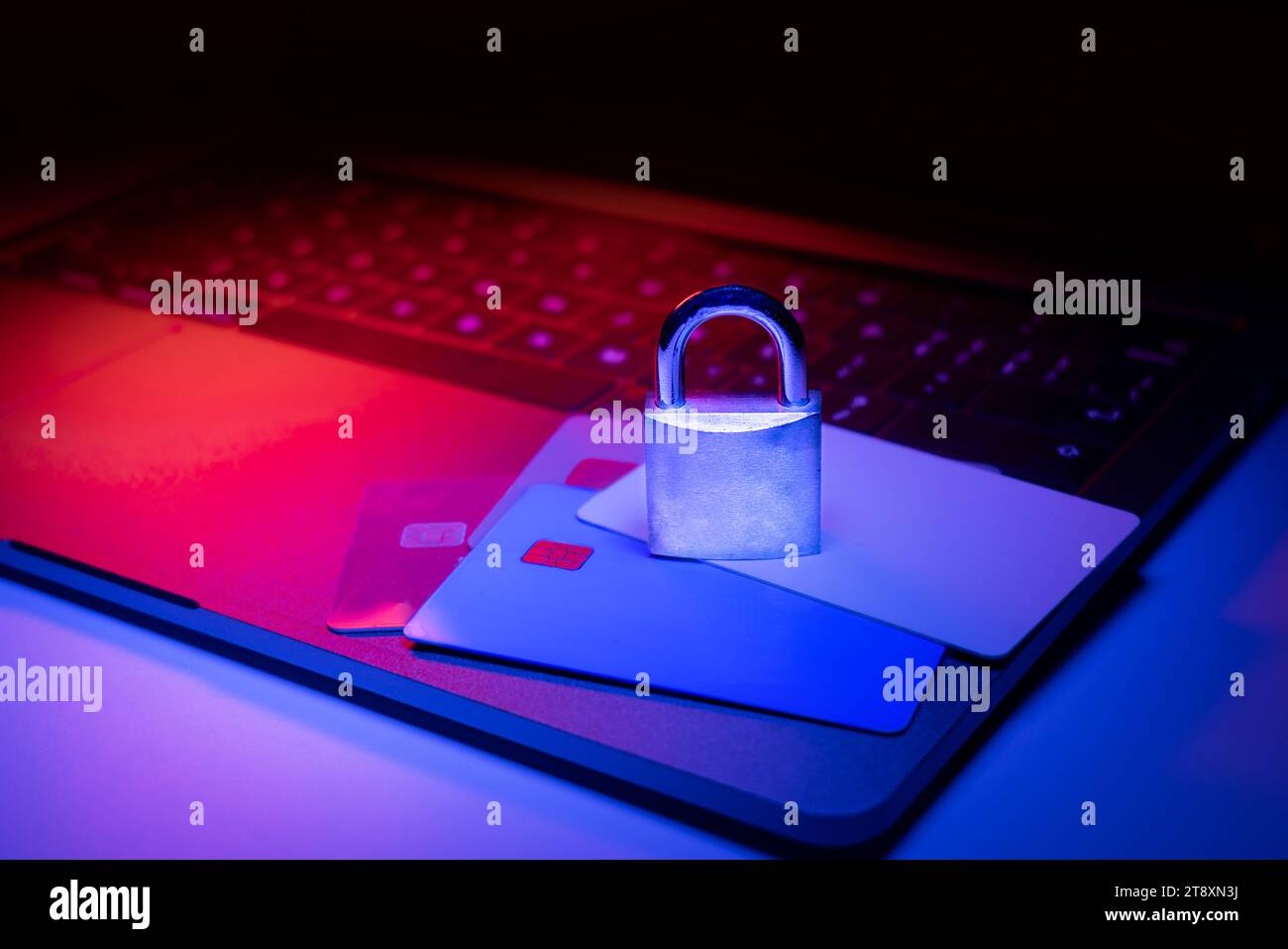 Closeup of a padlock on a laptop and credit card illuminated with blue ...
