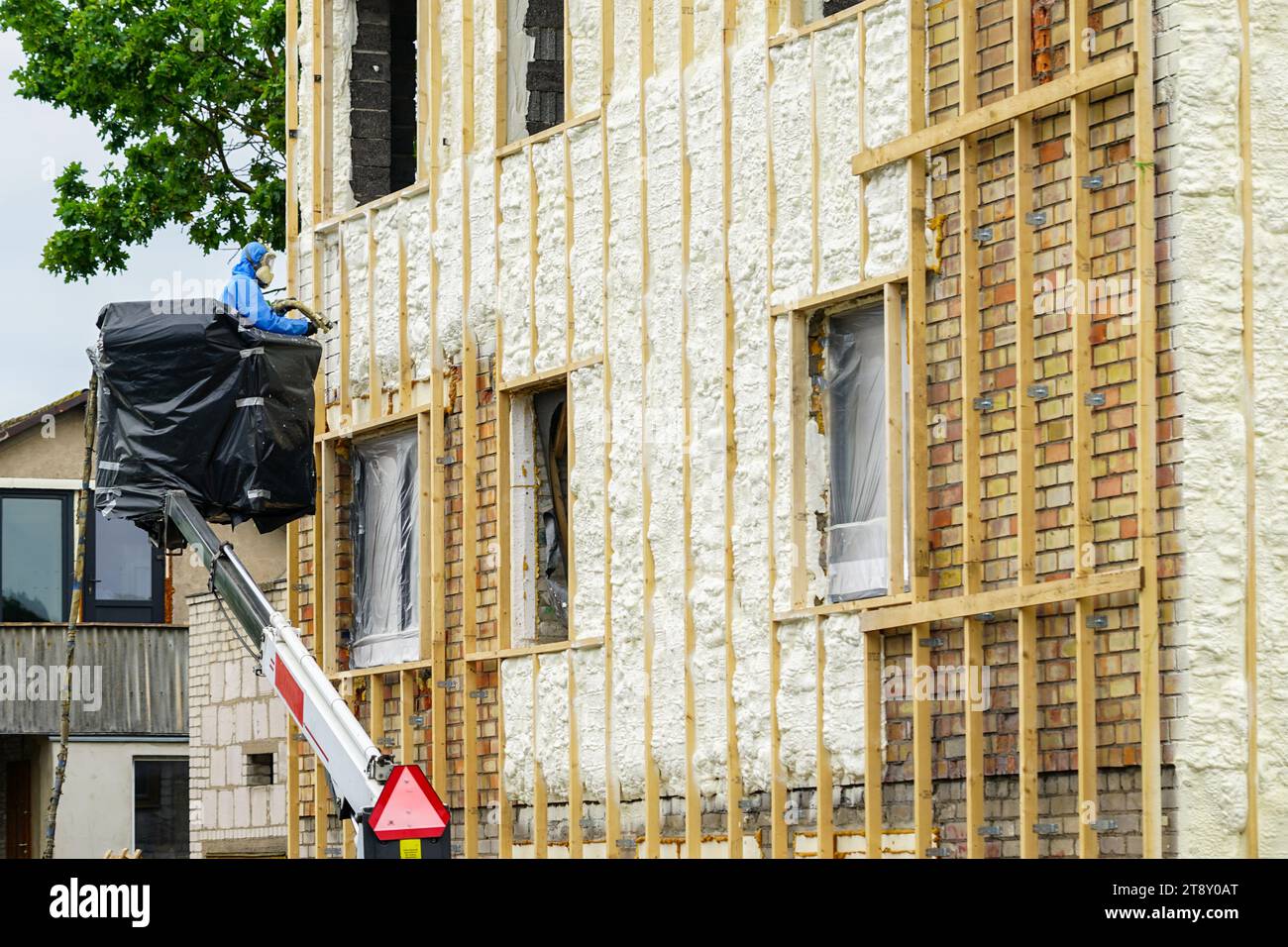 Technician spraying thermal insulation foam layer on the exterior wall ...
