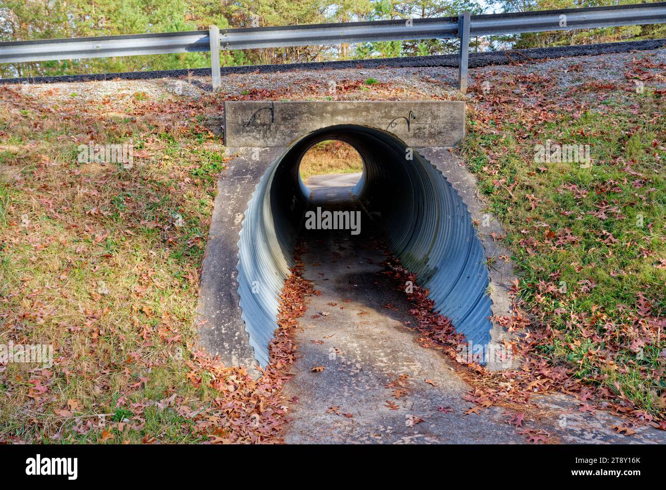 A paved walking trail that goes through a round galvanized tunnel under ...