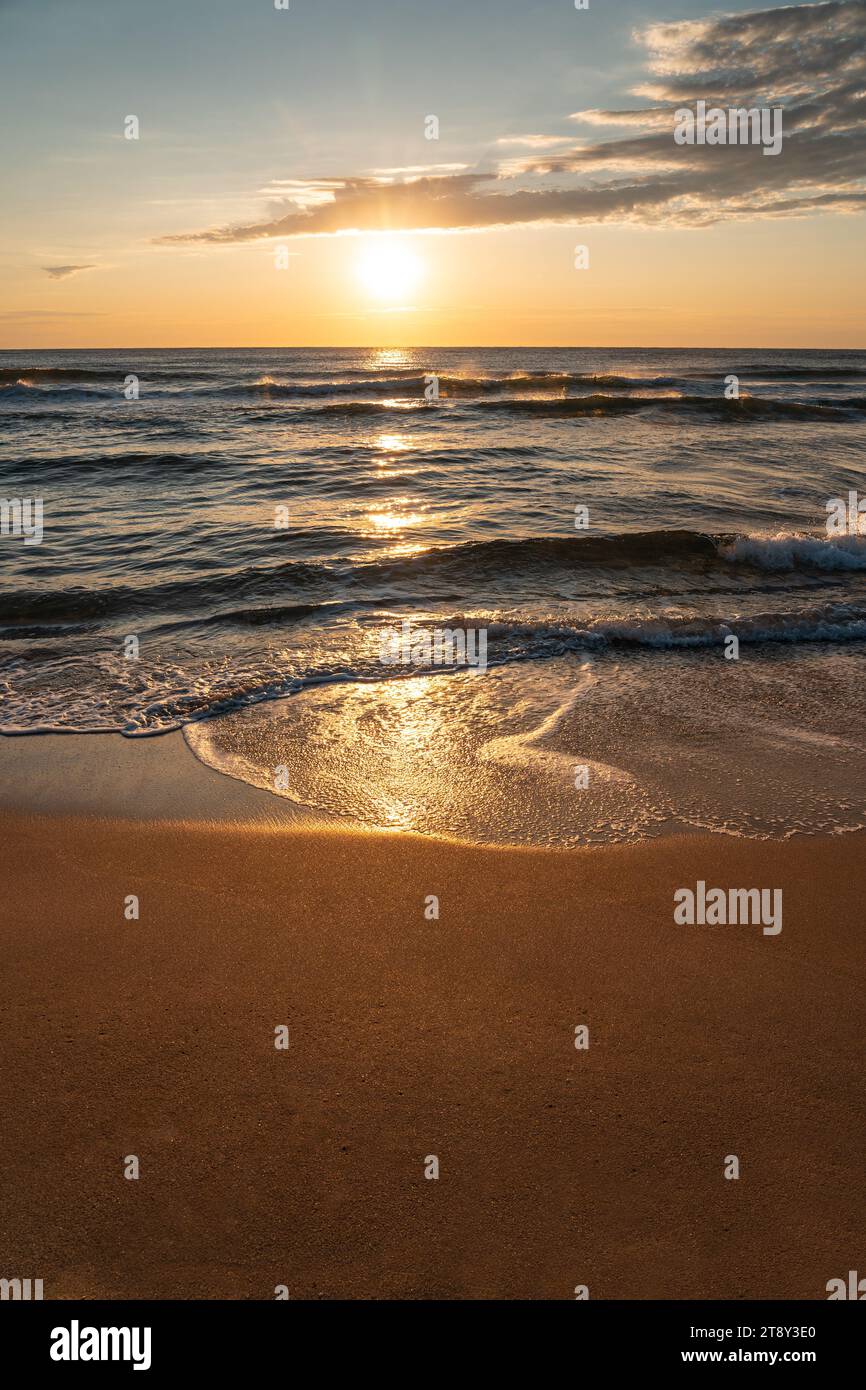 A stunning sunset over a sandy beach. The sun is setting over the ocean ...