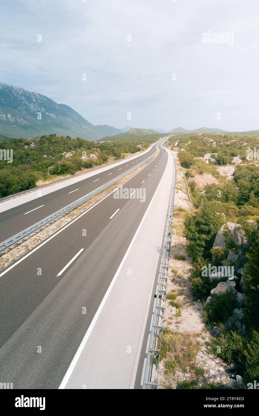 A long, winding highway stretching through a mountainous landscape. The ...