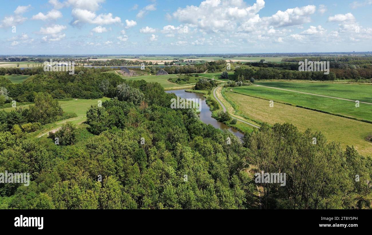 A scenic landscape featuring a river flowing through a lush field of ...