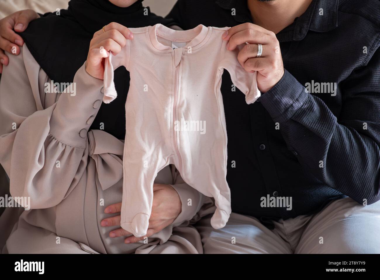 Husband and his wife holding newborn clothes for their fetus while in ...