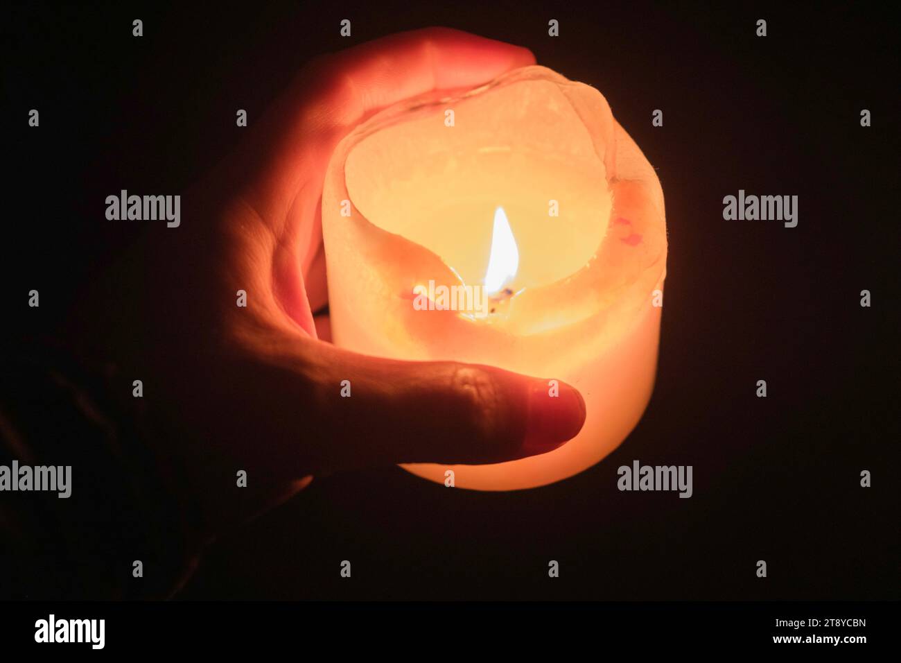 A hand holds a candle in the dark Stock Photo - Alamy