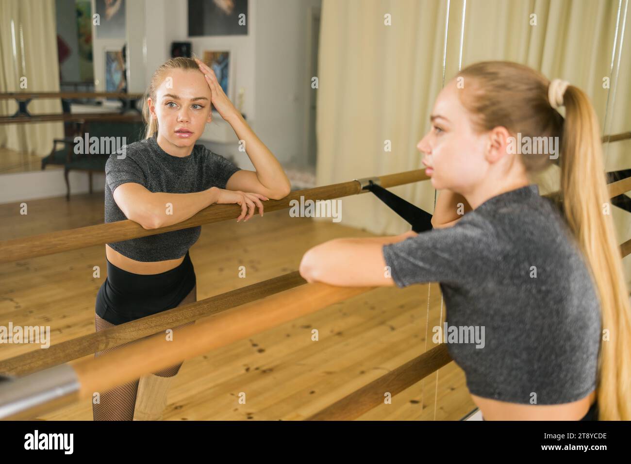 Female ballet dancer resting at barre and mirror in dance studio ...