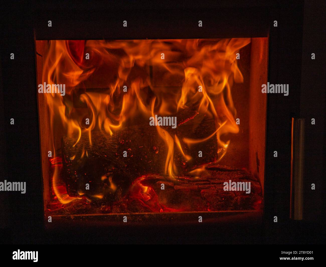 Intense flames burning wood inside a closed fireplace with visible ...