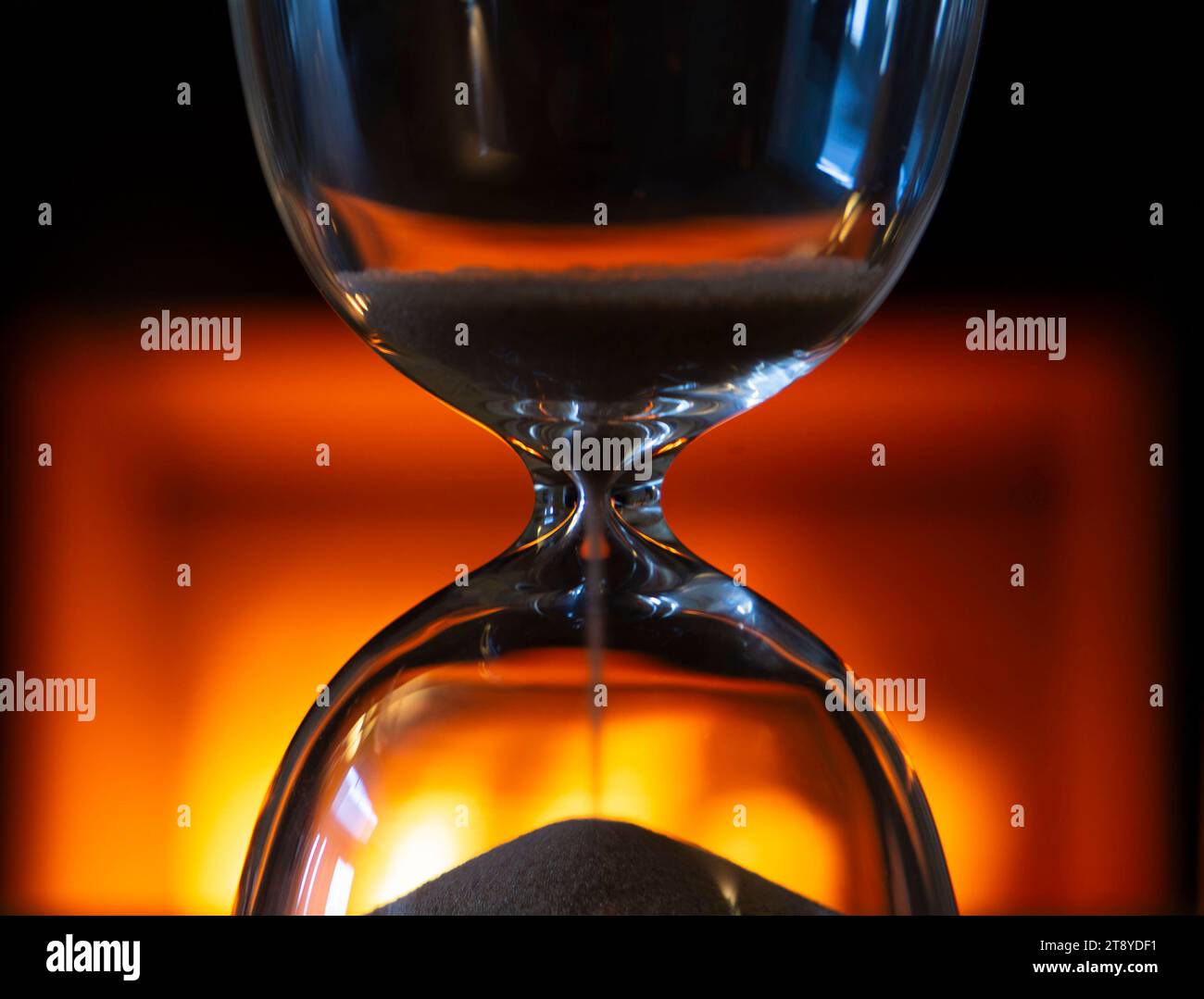 Close-up of an hourglass against a warm glowing background with sand ...
