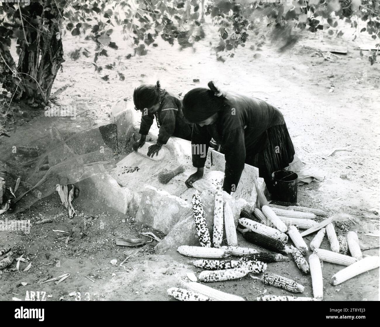 Mother & child using corn grinding bin on Navajo Indian Reservation ...