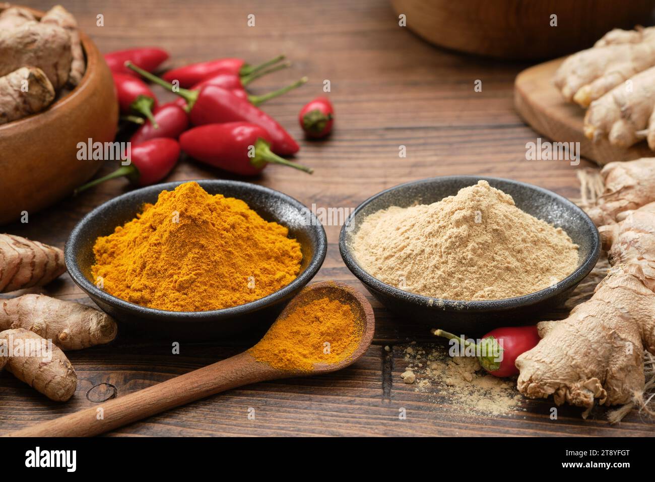 Bowls of ginger and curcuma ground to powder. Red chilli pepper pods ...
