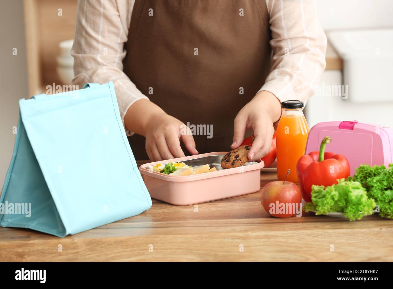 Mother packing meal in lunchbox for school on table at kitchen Stock ...