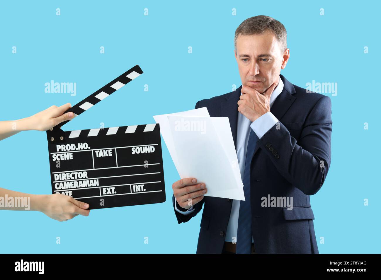 Mature actor reading film script and hands with clapperboard on blue ...