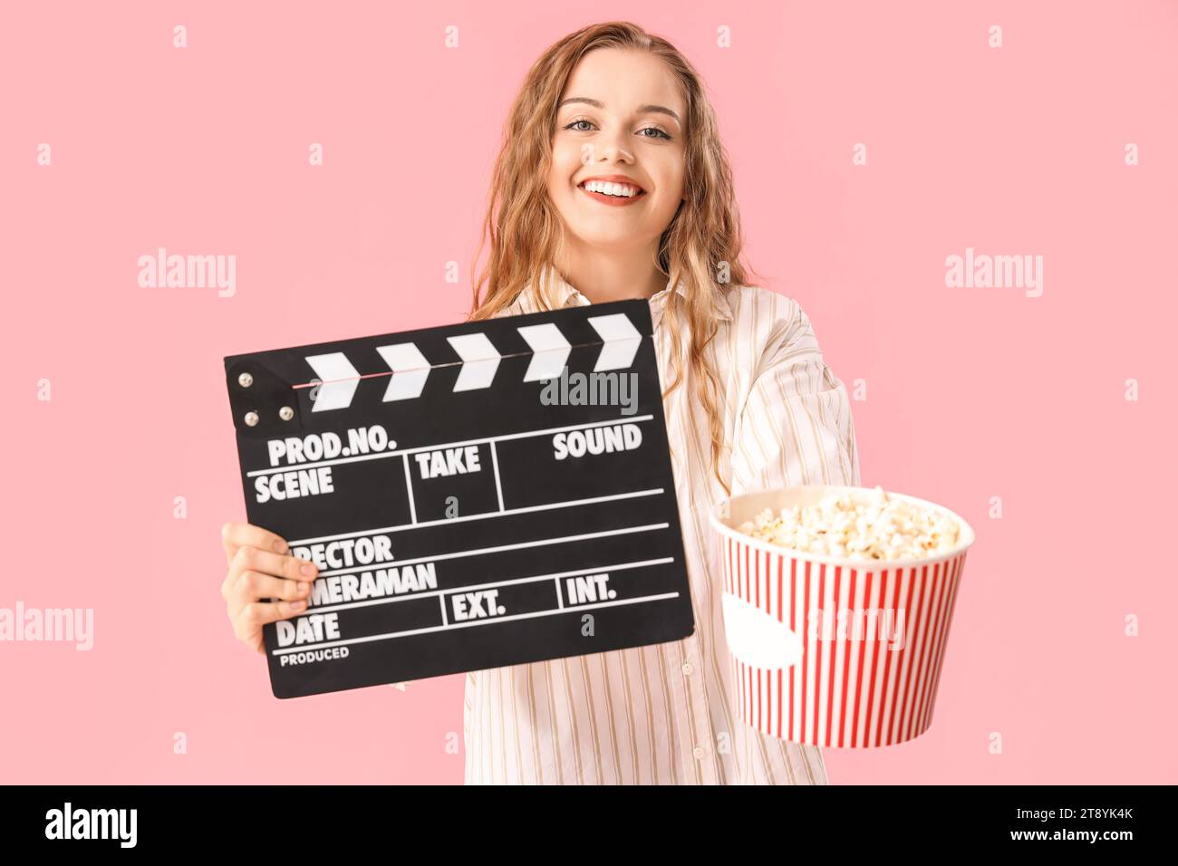 Beautiful actress with movie clapper and popcorn on pink background ...