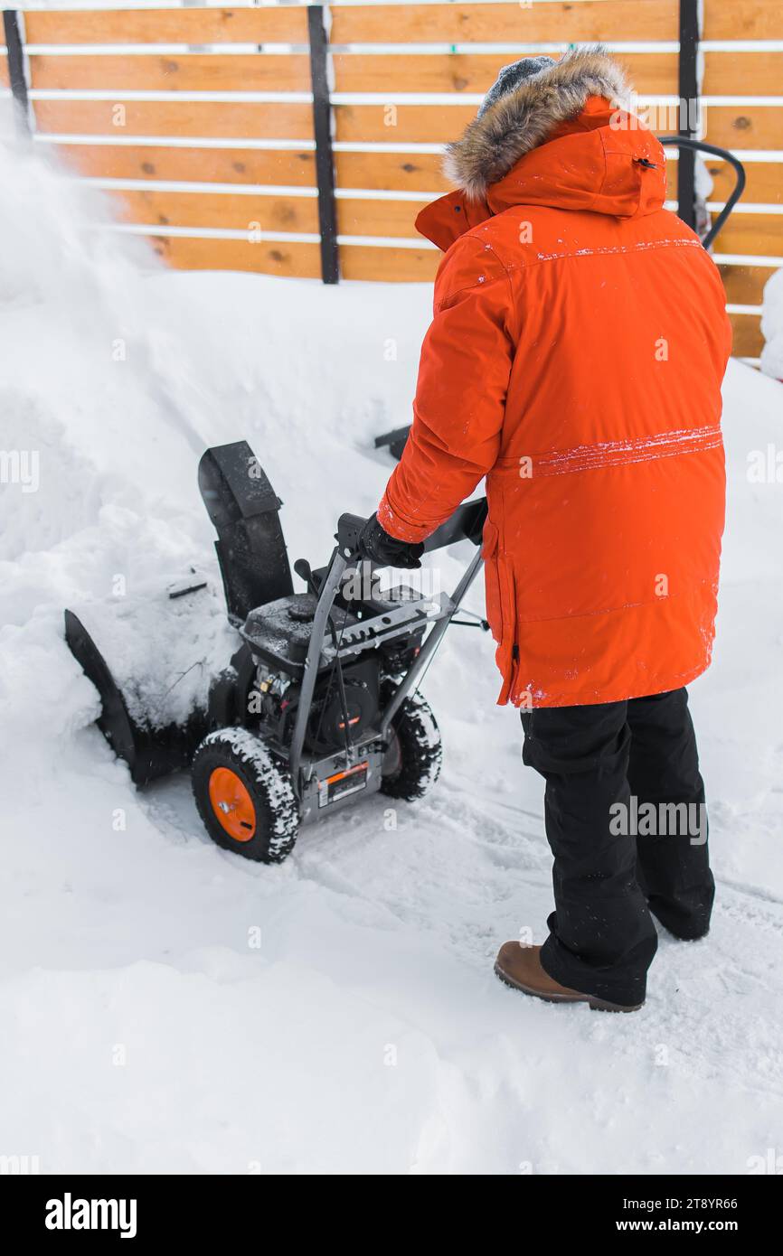 A man clear snow from backyard with snow blower. Winter season and snow ...
