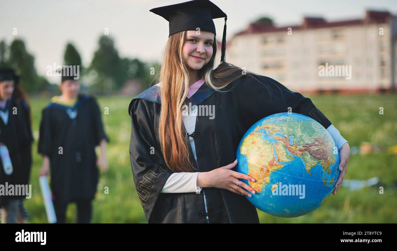 Graduate student girl poses with a globe in a meadow Stock Photo - Alamy