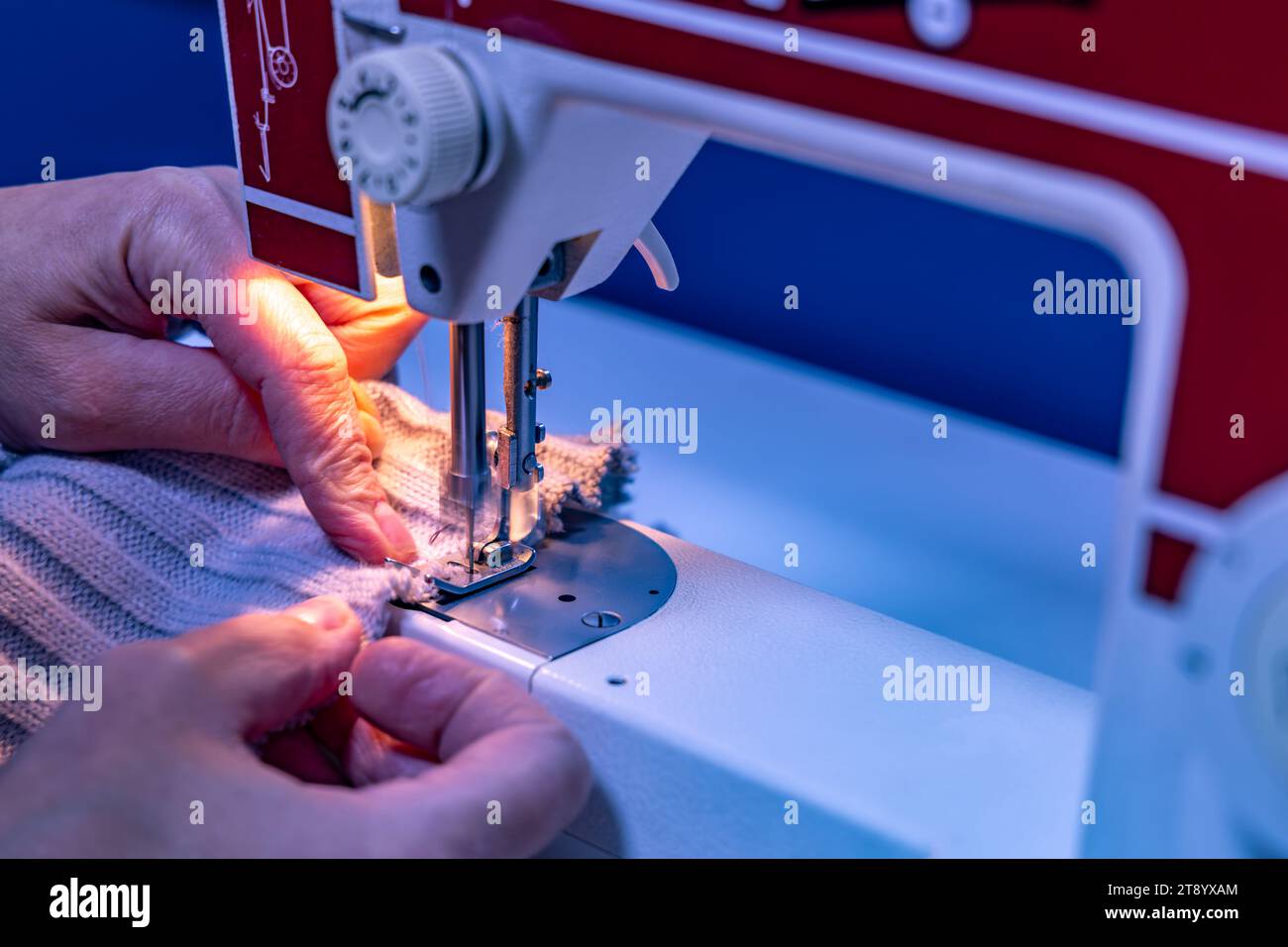 Sewing on a machine at home in a tailor's shop, repairing old clothes ...
