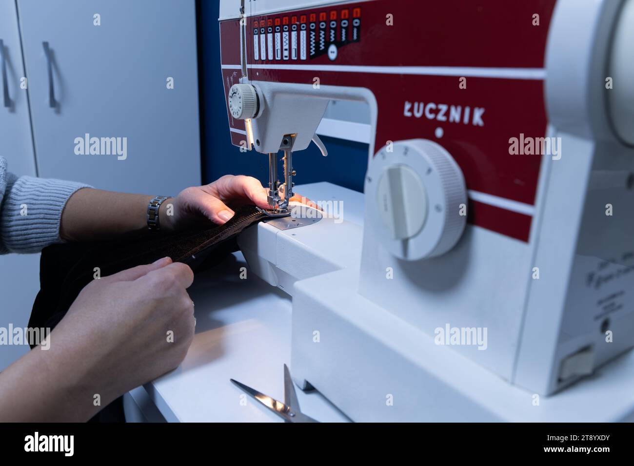 Sewing on a machine at home in a tailor's shop, repairing old clothes ...