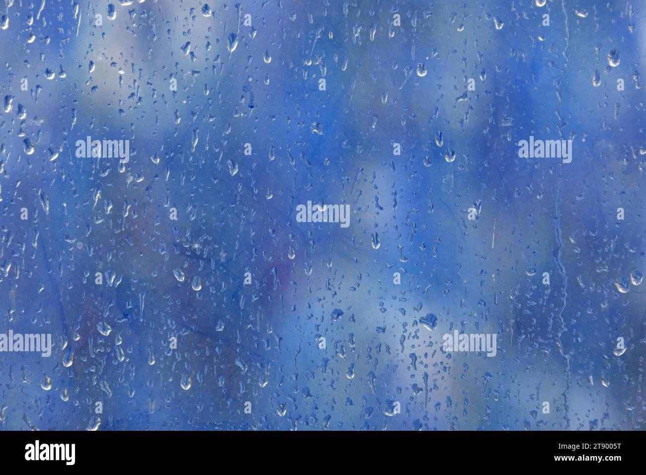 Raindrops on the window glass. Blurred colored background outside the ...