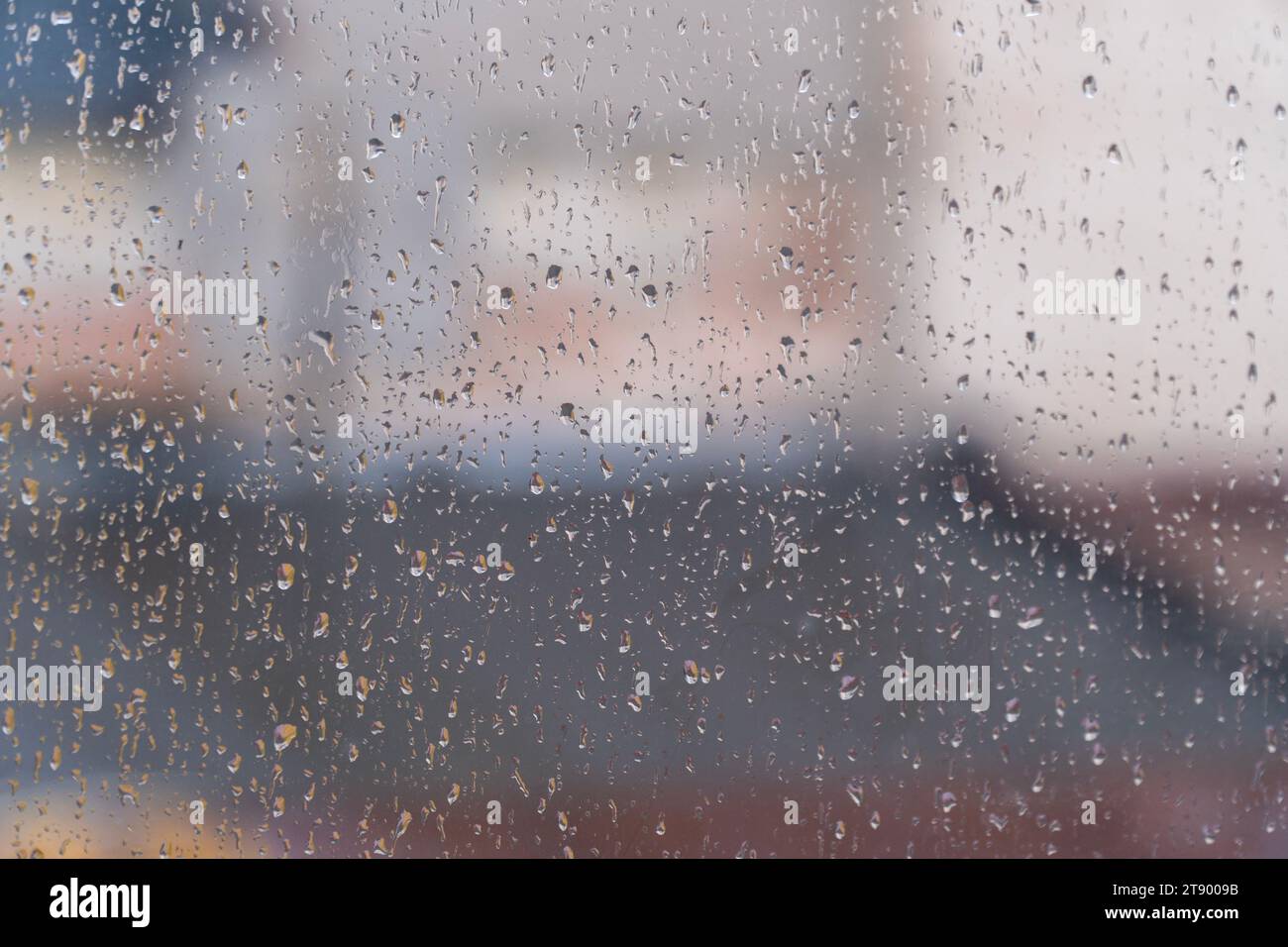 Raindrops on the window glass. Blurred colored background outside the ...