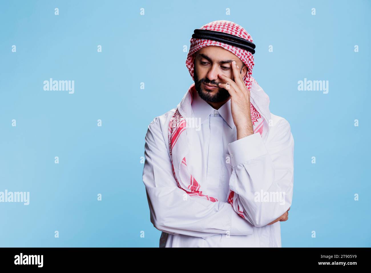 Pensive muslim man in thobe and ghutra headscarf standing in thoughts ...