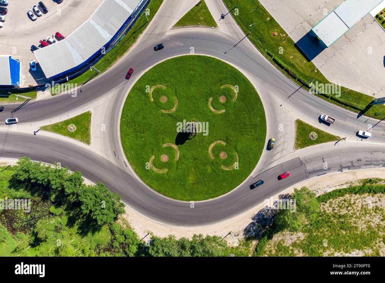 Aerial view of a roundabout with a large green flowerbed and cars ...