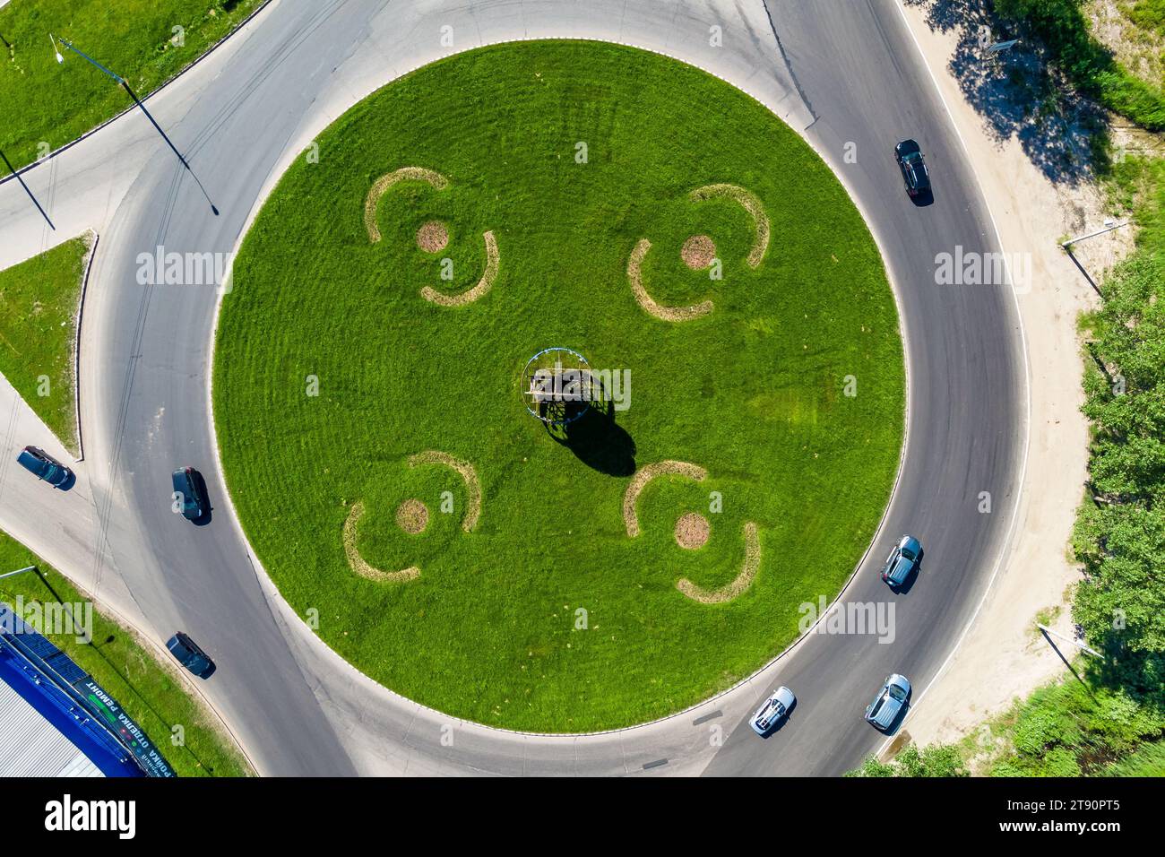 Aerial view of a roundabout with a large green flowerbed and cars ...