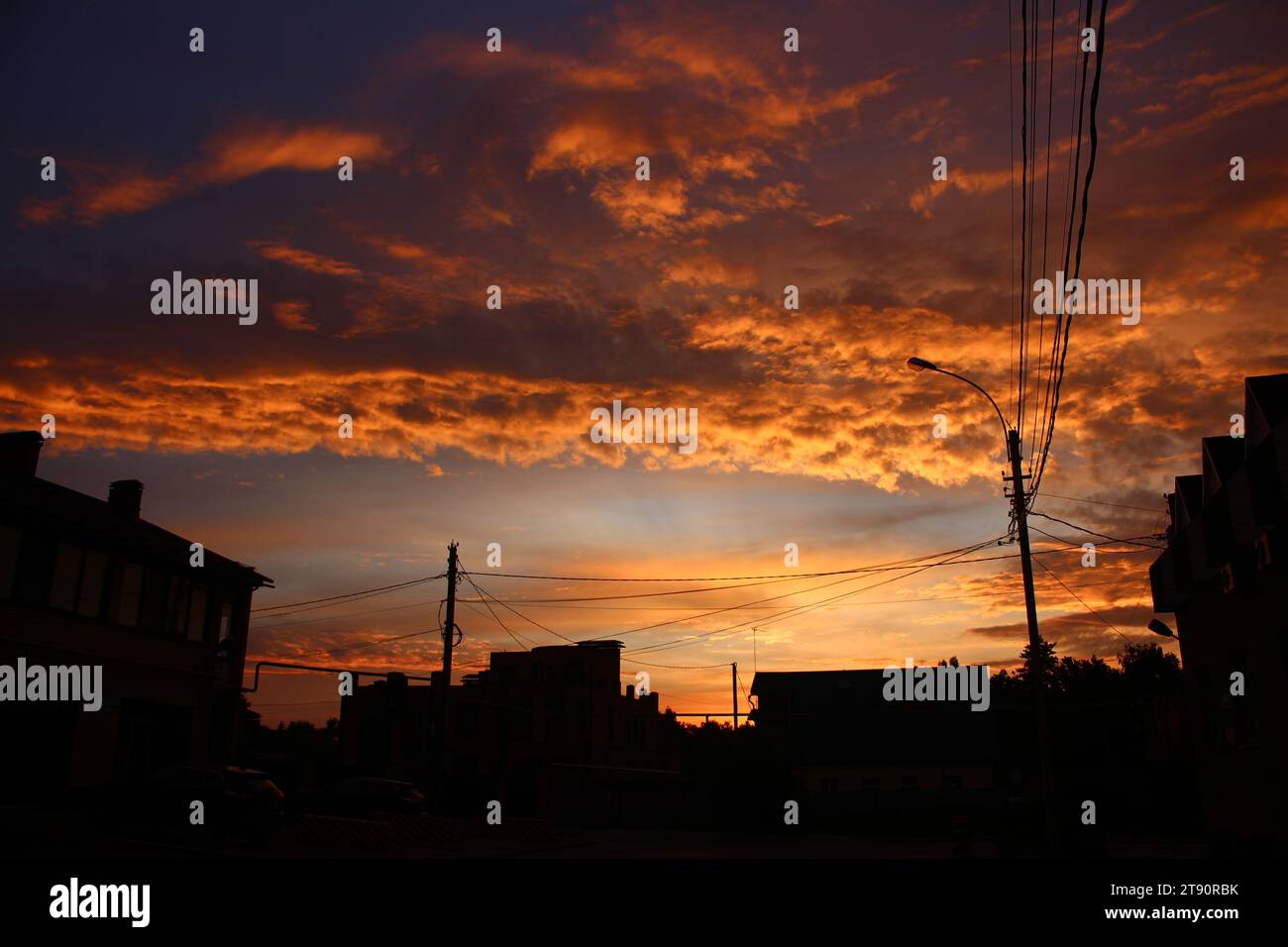 Red fiery sunset in a cloudy sky with city power lines in the ...