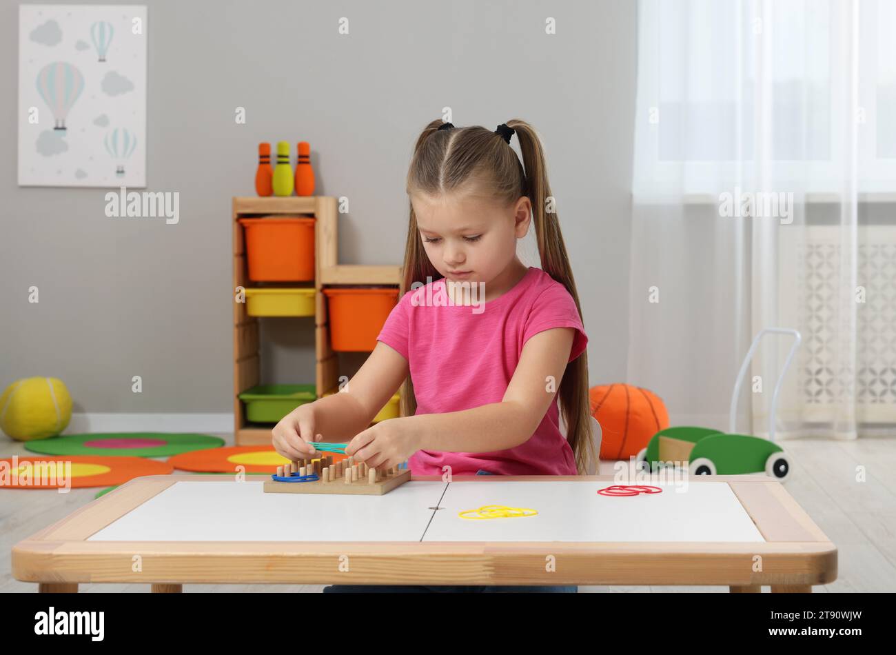 Motor skills development. Girl playing with geoboard and rubber bands ...