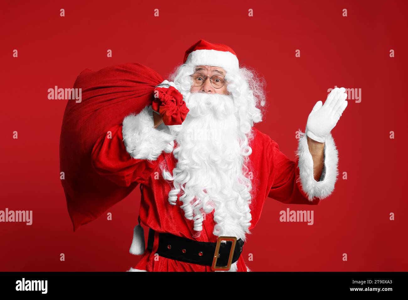 Santa Claus with bag of Christmas presents waving hello on red ...
