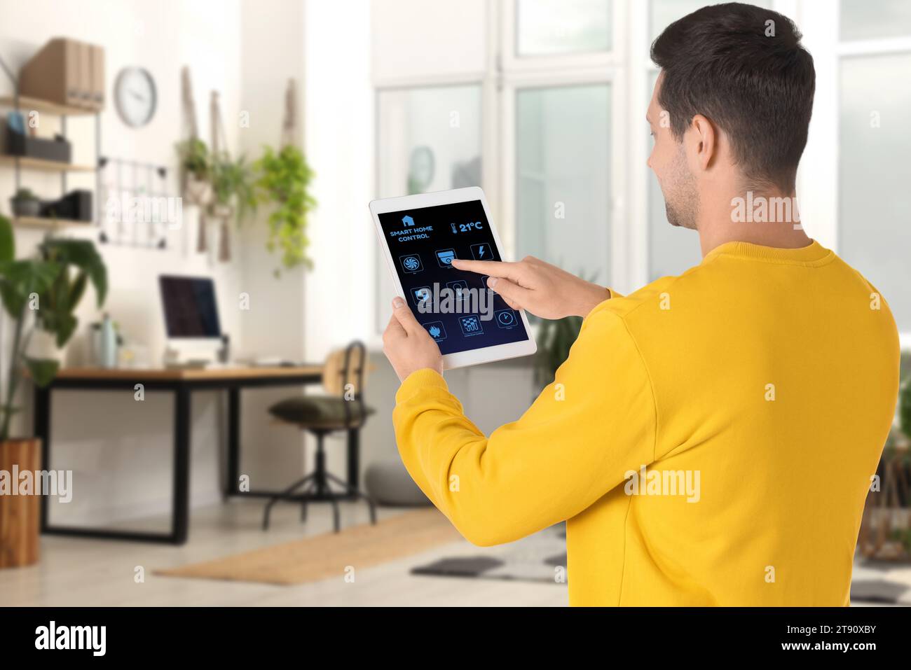 Man Using Smart Home Control System Via Application On Tablet Indoors