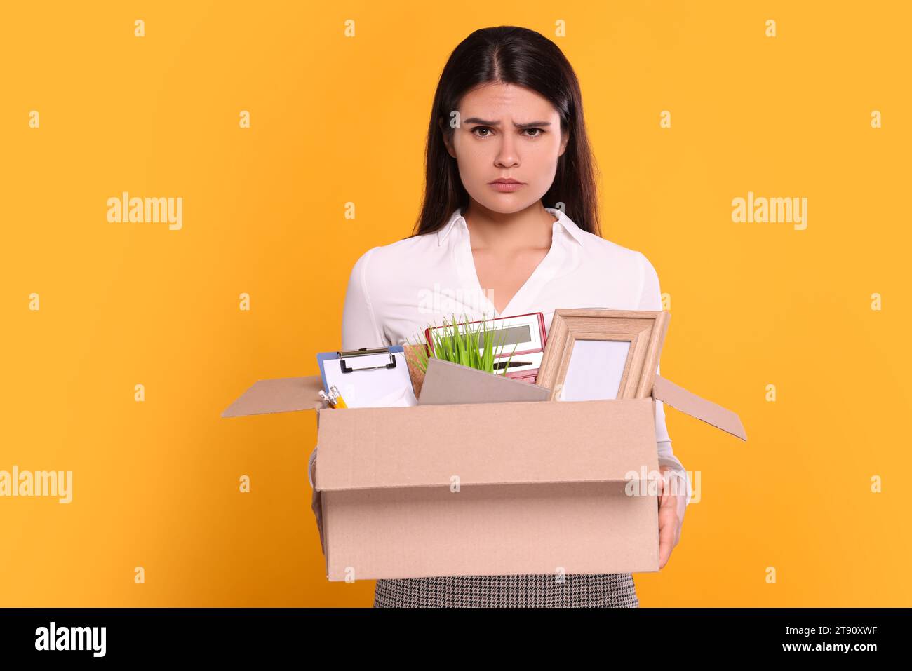 Upset unemployed woman with box of personal office belongings on orange ...