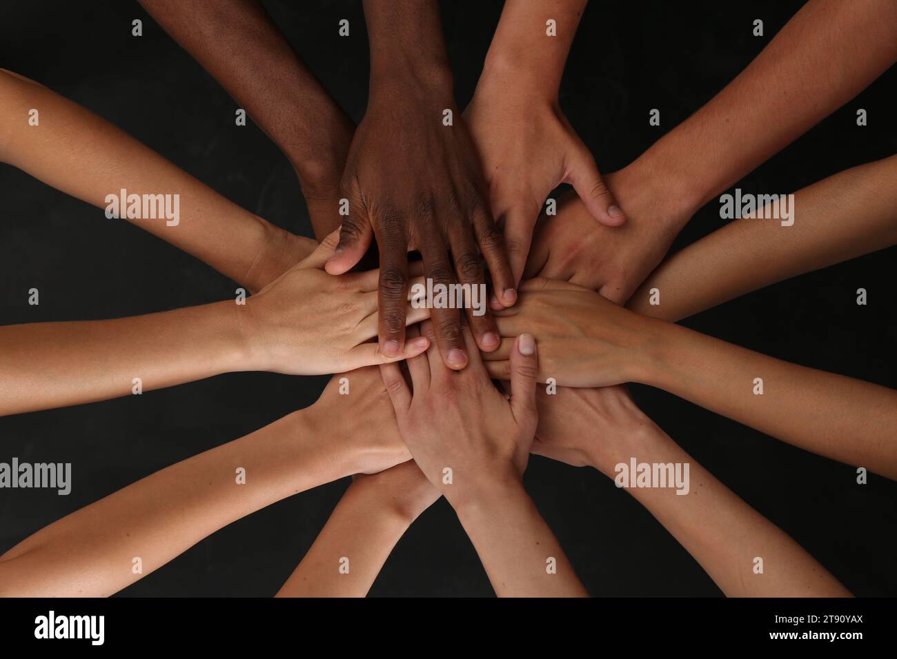 Group of multiracial people joining hands together on black background, closeup Stock Photo - Alamy