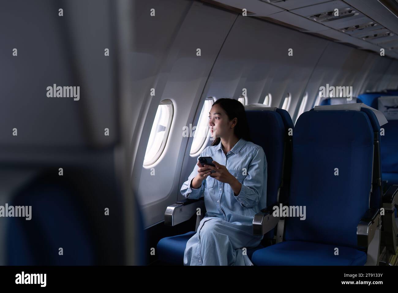Asian people female person onboard, airplane window, using mobile while ...