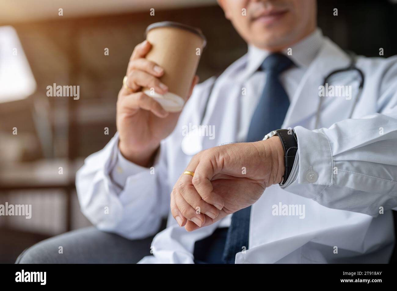 A professional senior male doctor is checking time on his wristwatch ...