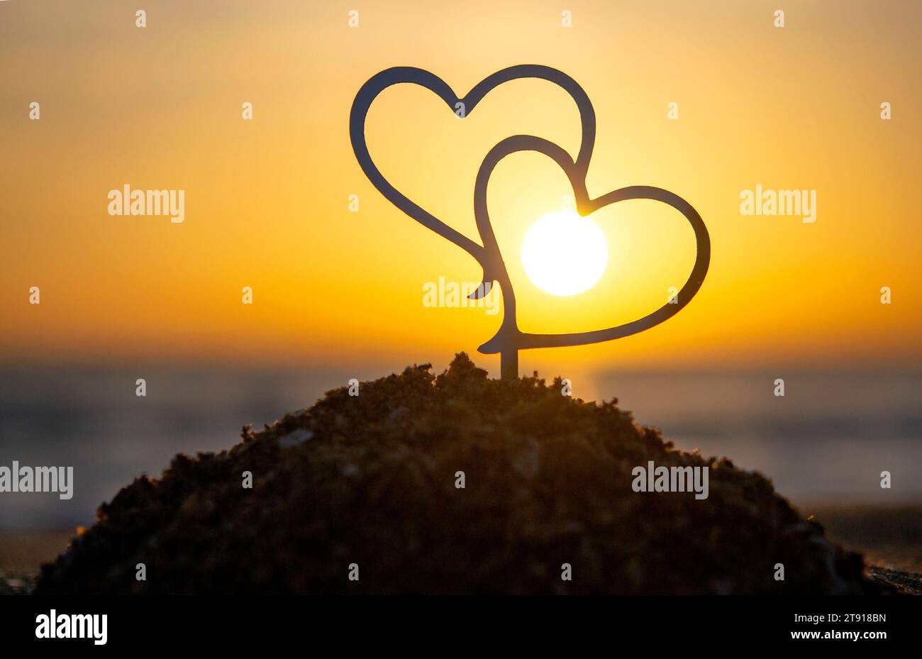 Two black outlines of heart at dawn and sunset on sky on seashore ...