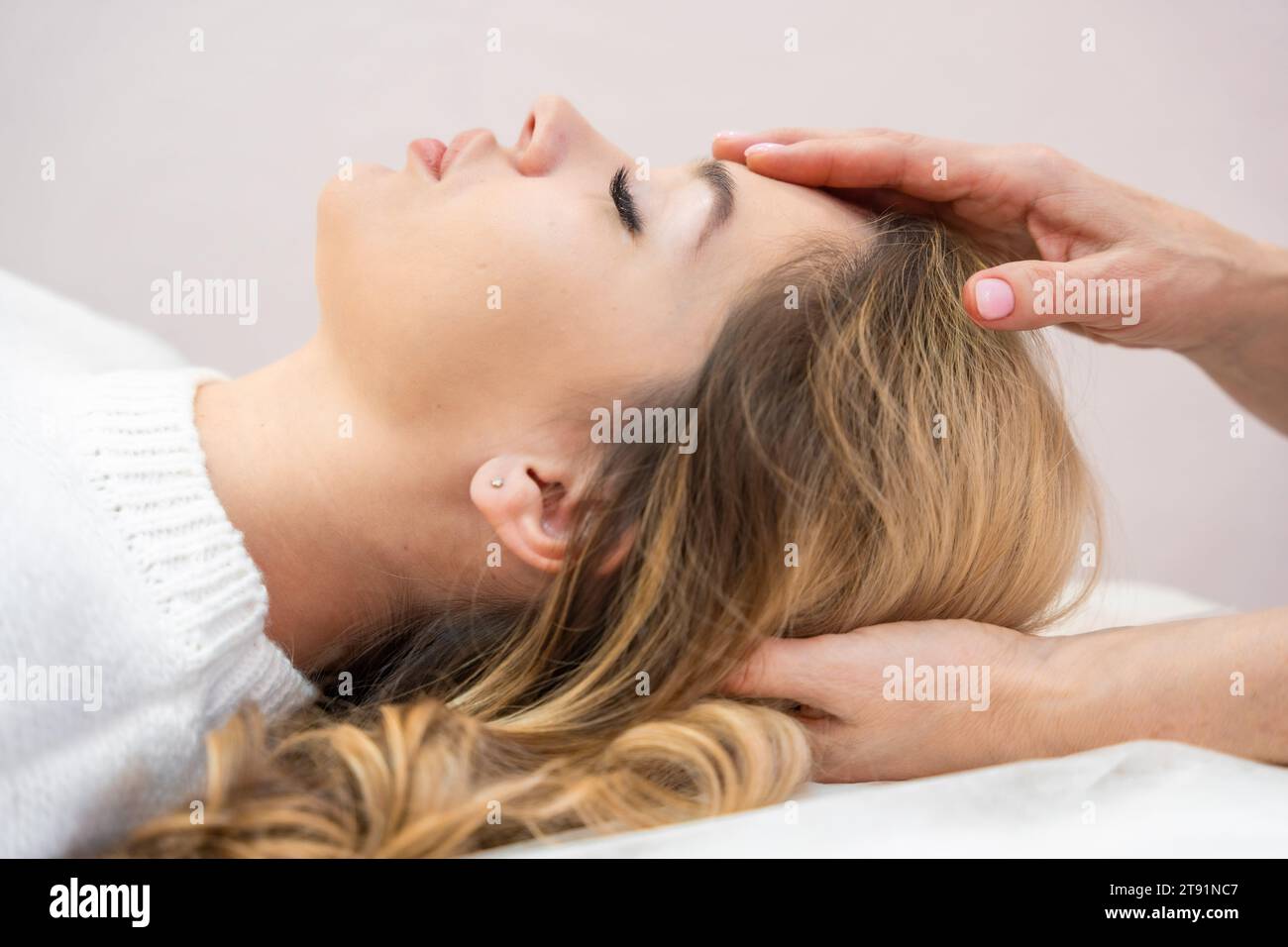 Healer performing set of 32 points of access bars on young woman head ...