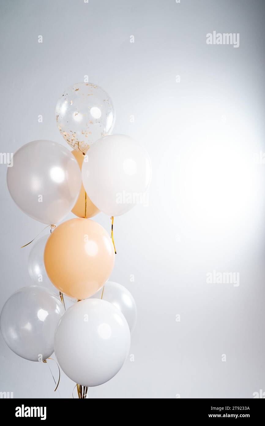 Balloons in white, beige and transparent colors on a gray background ...