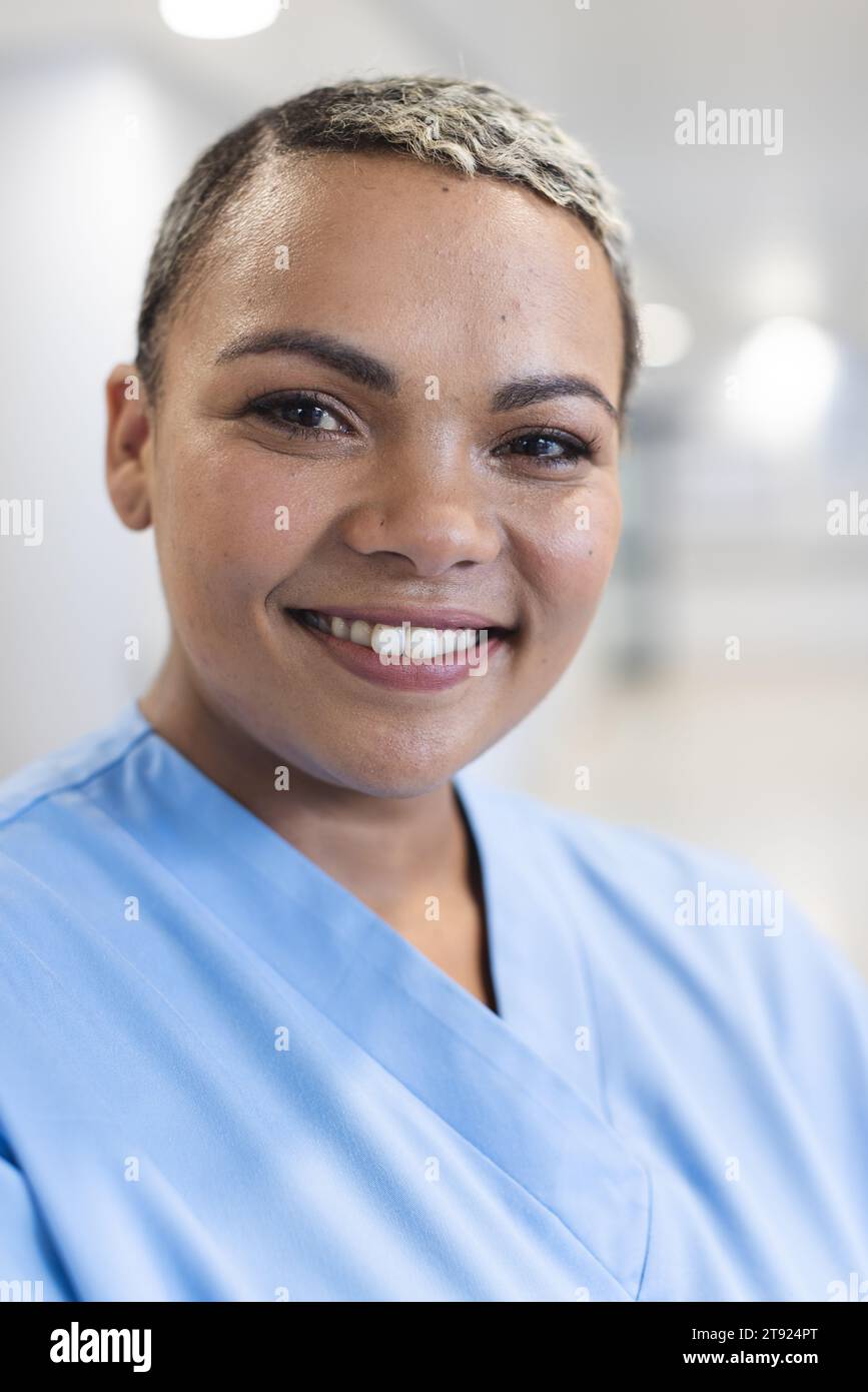 Portrait of happy biracial female doctor with short hair wearing scrubs ...