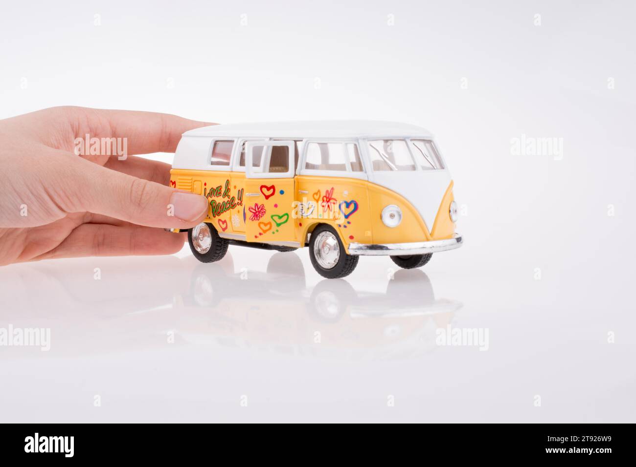 Hand holding a yellow Peace Van on a white background Stock Photo - Alamy