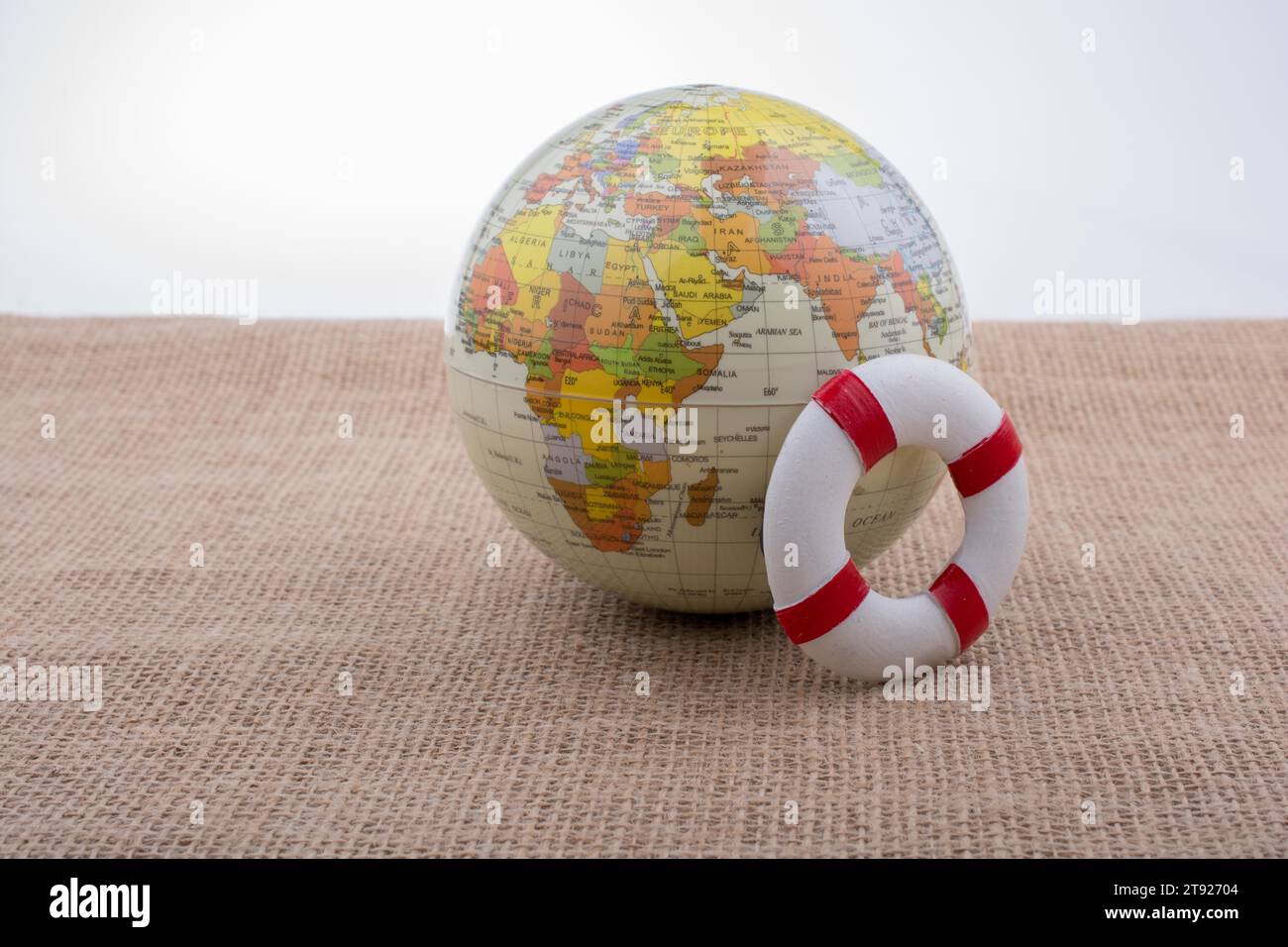 Life preserver beside a globe placed on canvas background Stock Photo ...