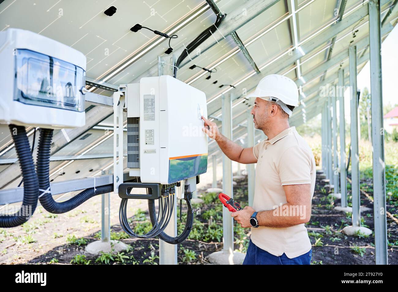 Professional worker checking voltage on solar inverter. Male using ...
