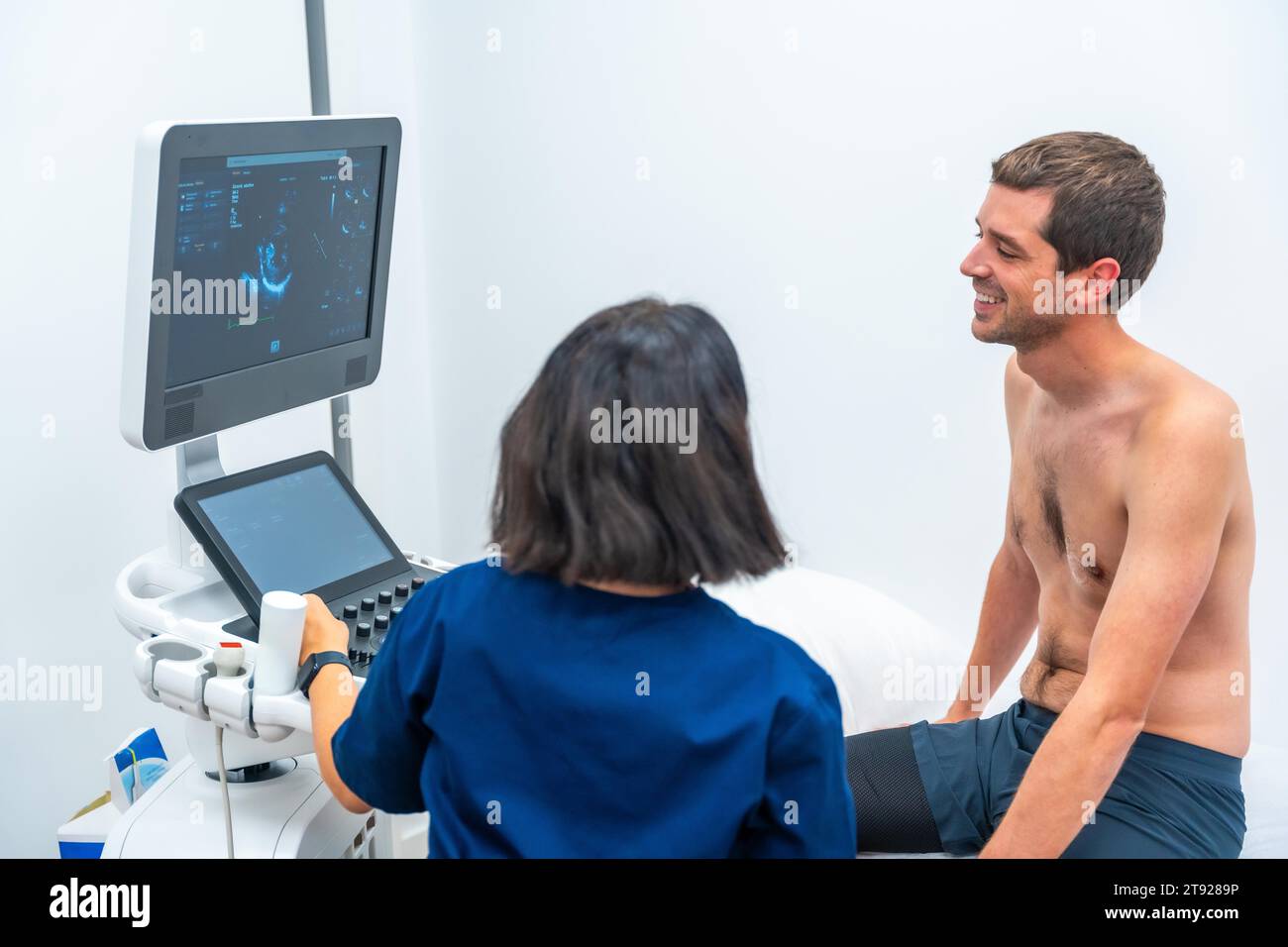 Female cardiologist doctor performing an echocardiogram on a patient in ...