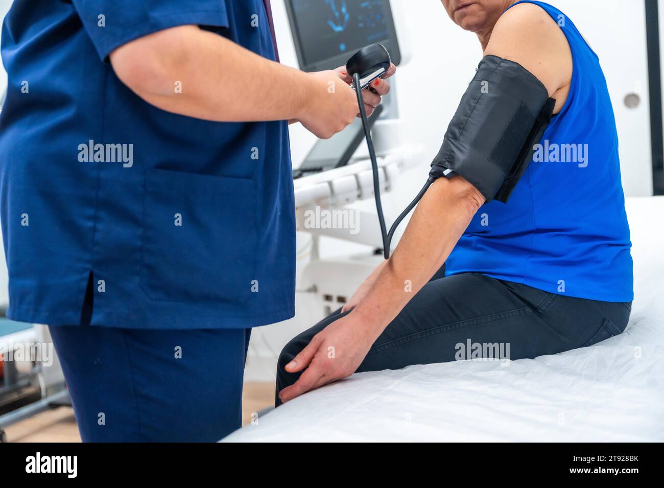Doctor measuring the blood pressure of a woman sitting on a stretcher ...