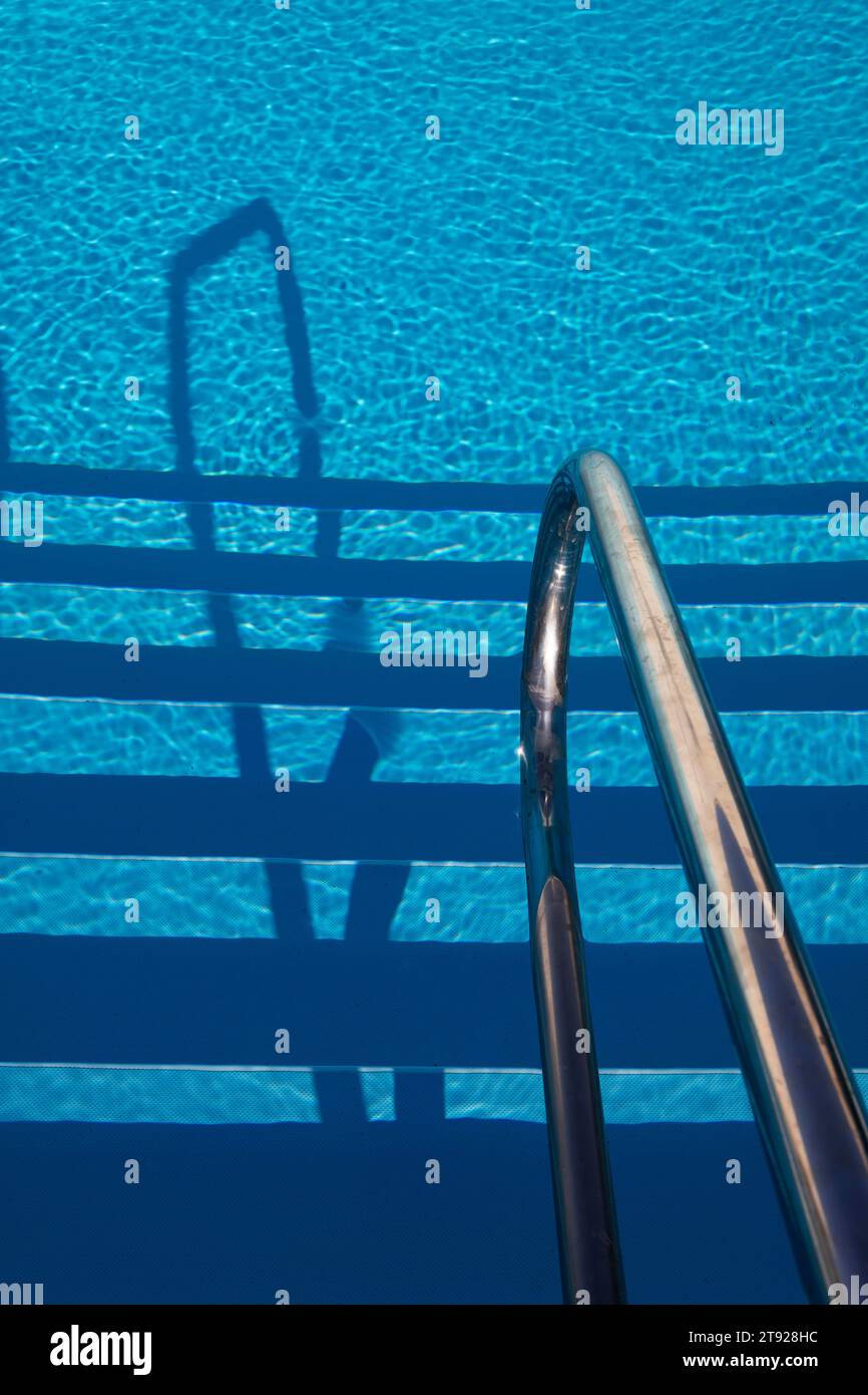 Water surface with light reflections and railing in a swimming pool ...