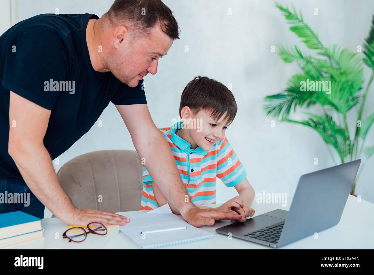 Man helping child studying at computer Stock Photo - Alamy