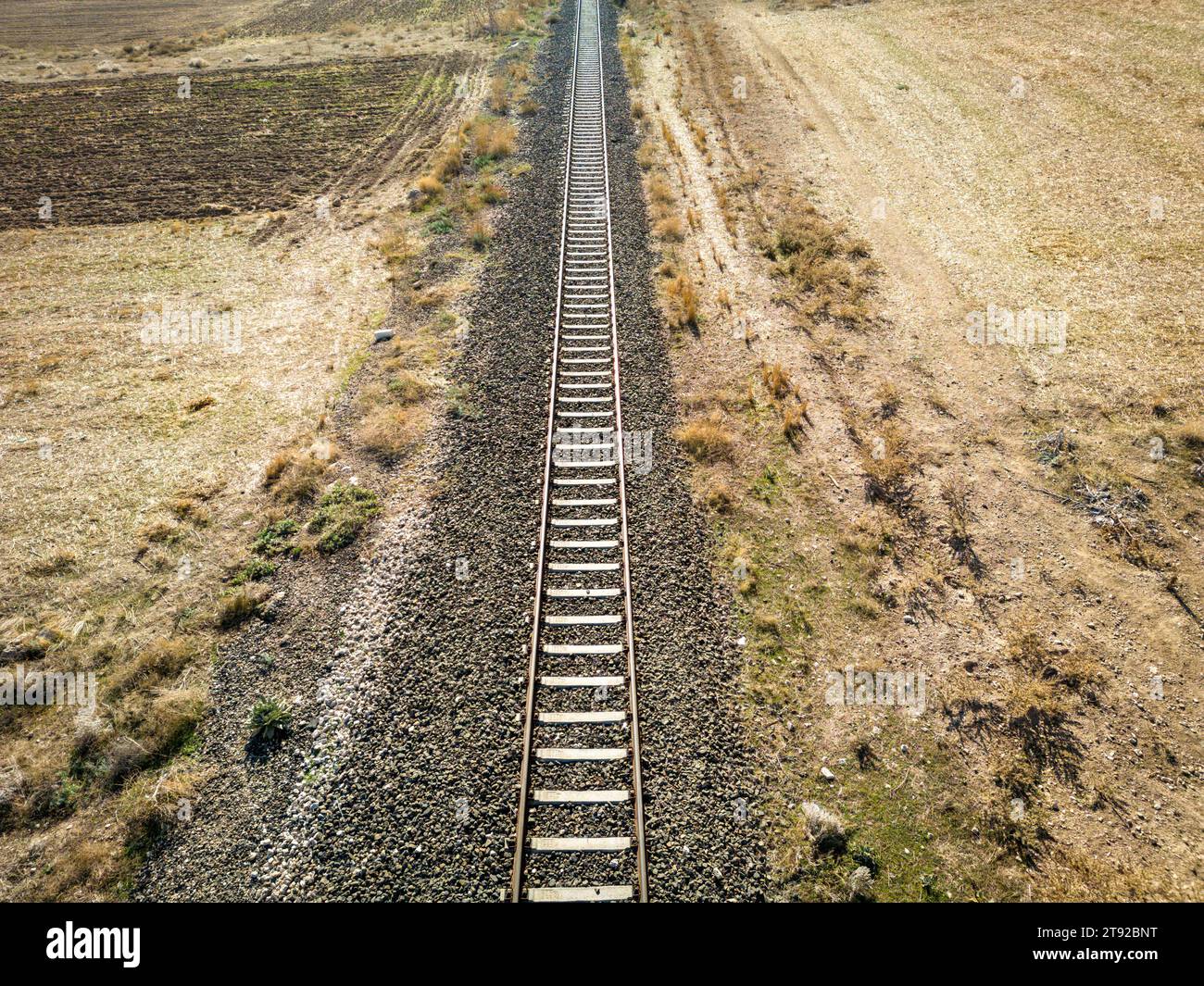 Top view of the train track passing through the arid land, taken with a ...