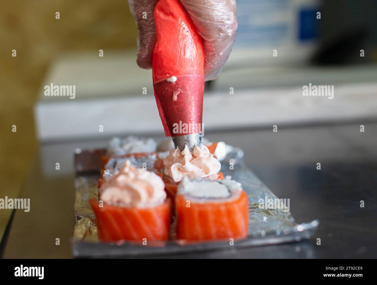 Close-up of the sushi making process. Using a culinary syringe, squeeze ...