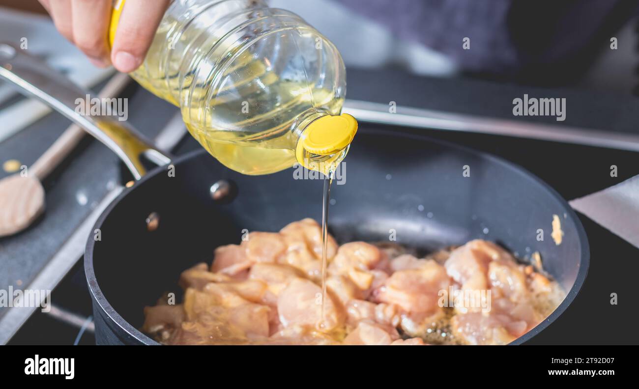 Cook pouring oil into a hot black saucepan Stock Photo - Alamy