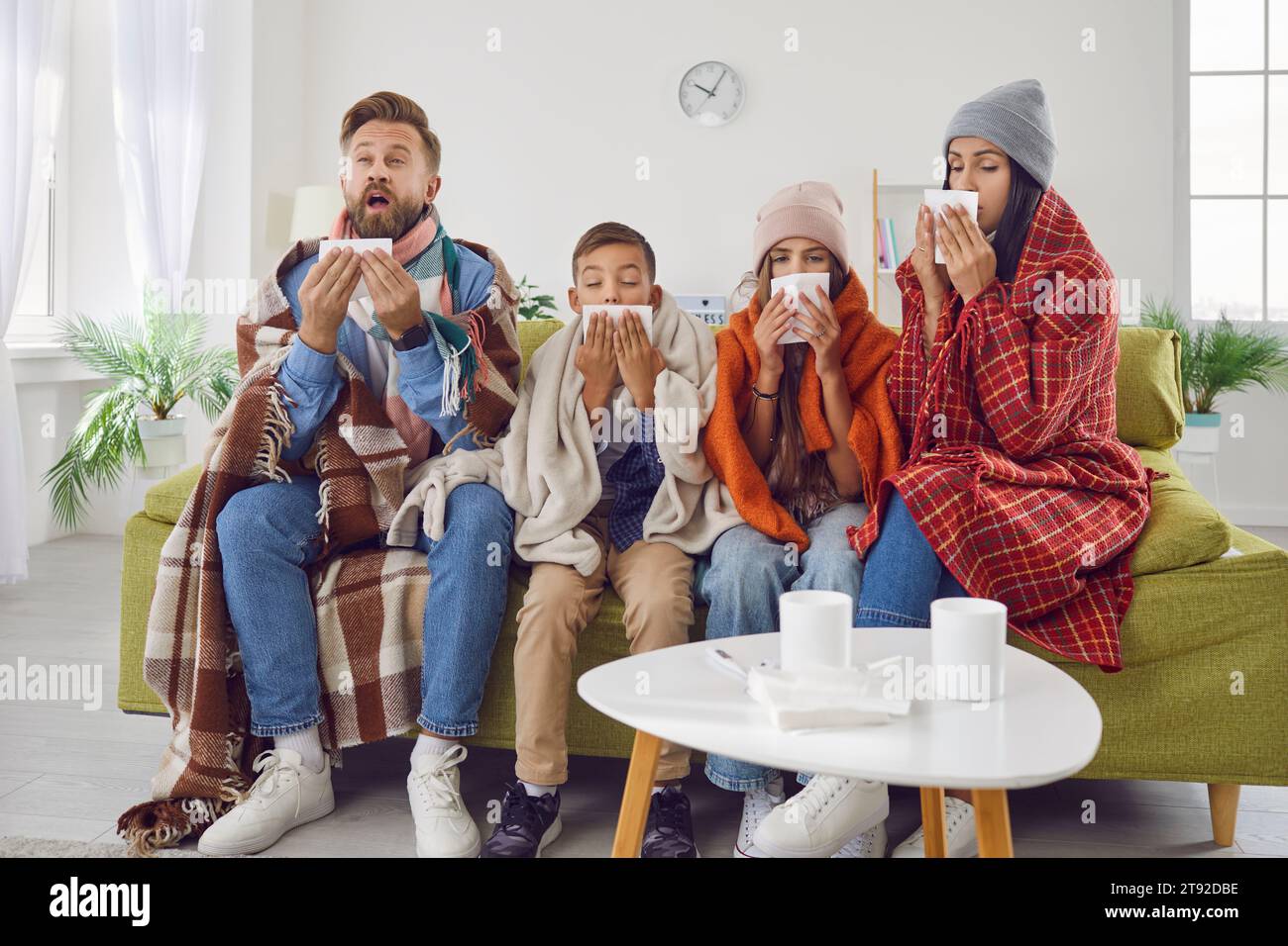 Sick mom, dad and children sitting on sofa and sneezing in paper ...