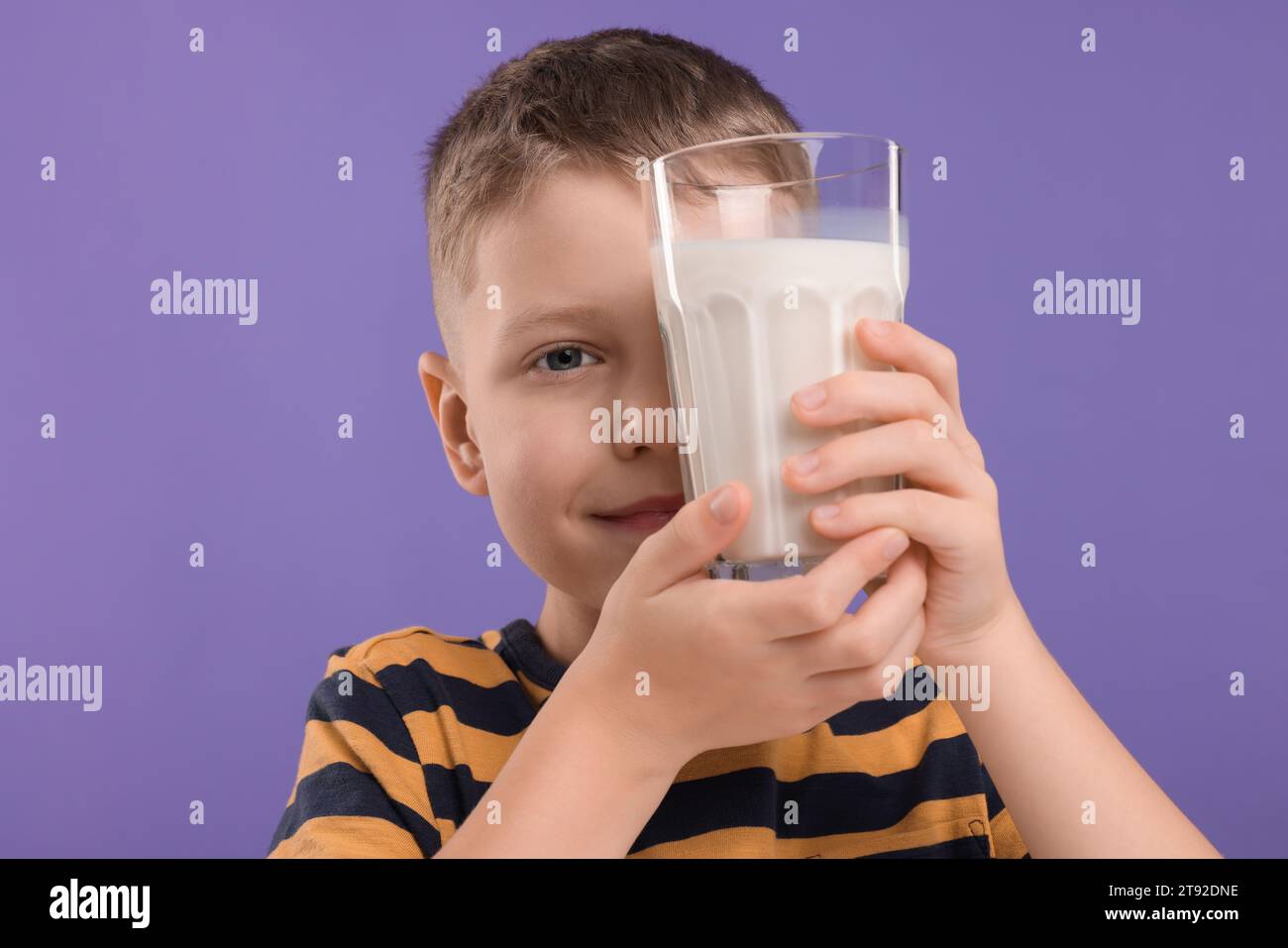 Cute boy with glass of fresh milk on violet background Stock Photo - Alamy