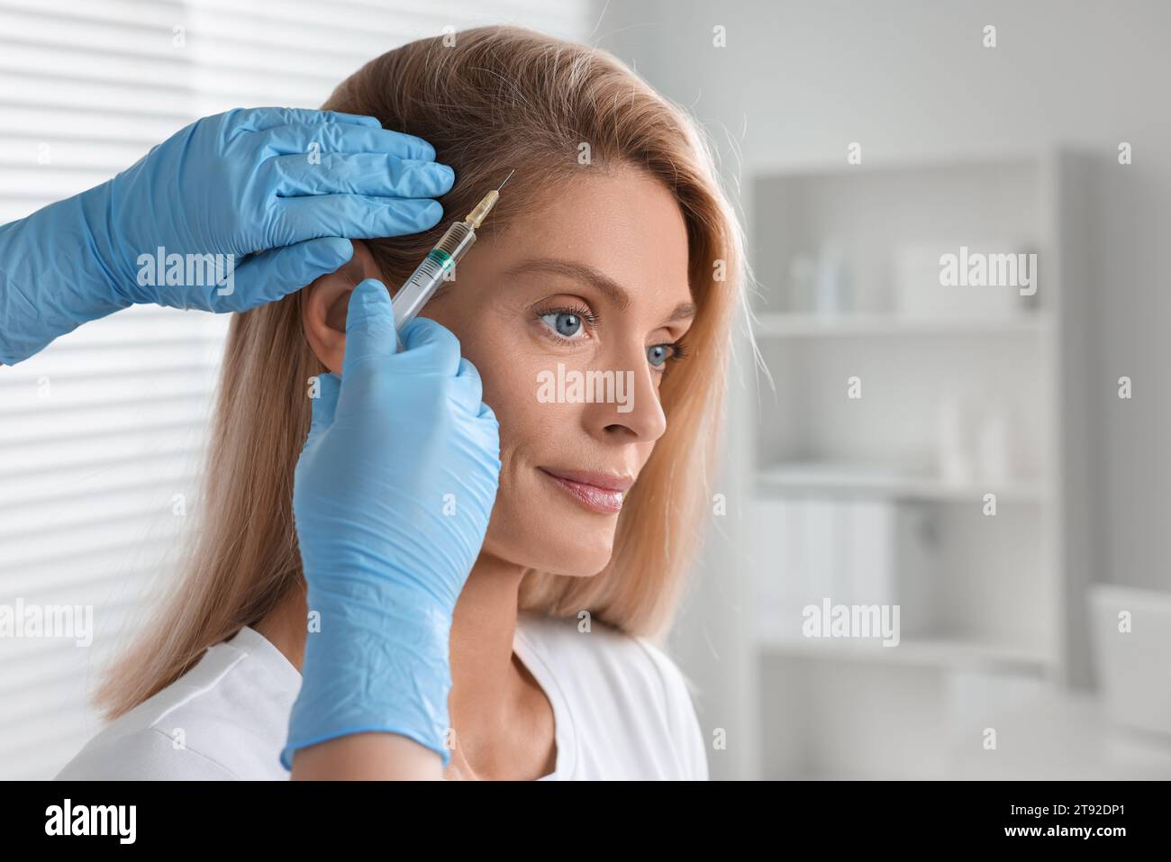 Trichologist giving injection to patient in clinic, closeup. Space for ...